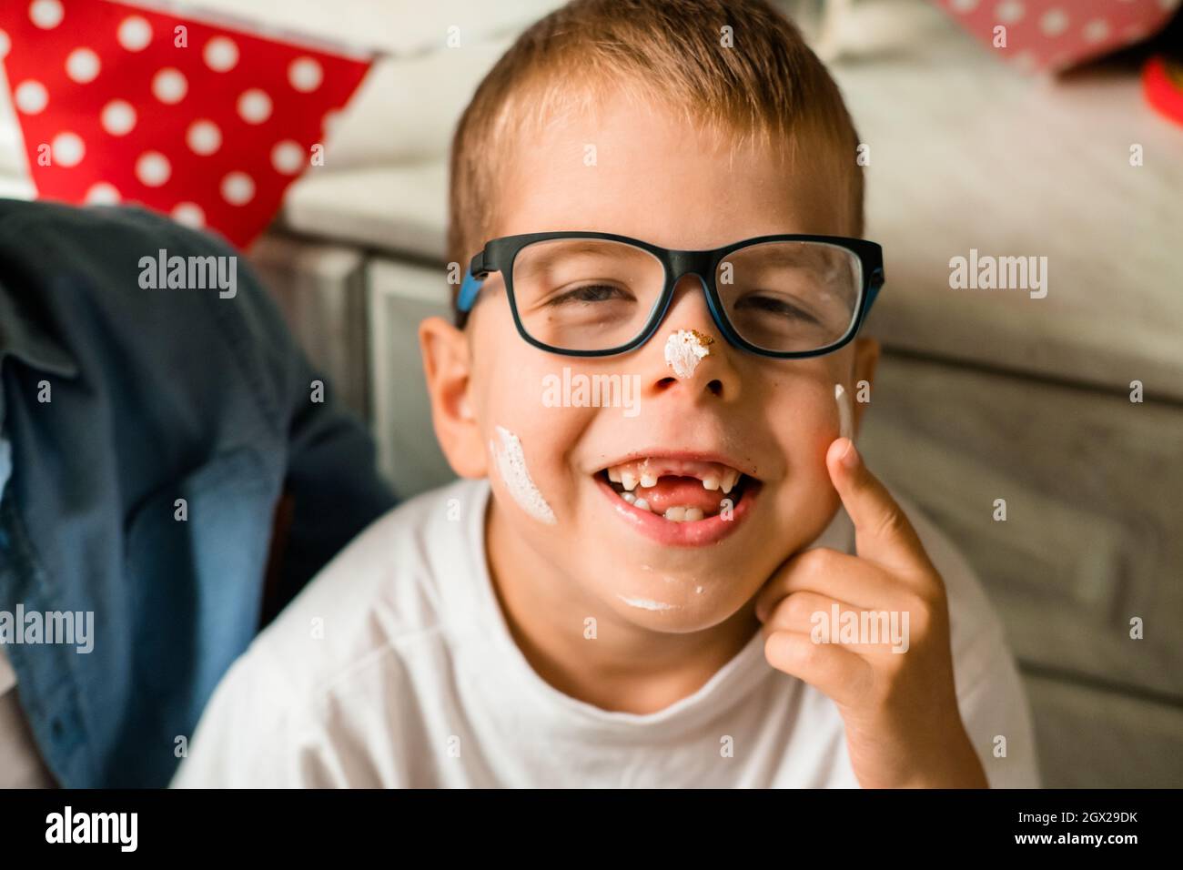 boy celebrates his birthday. The boy is covered with a cake on his face ...