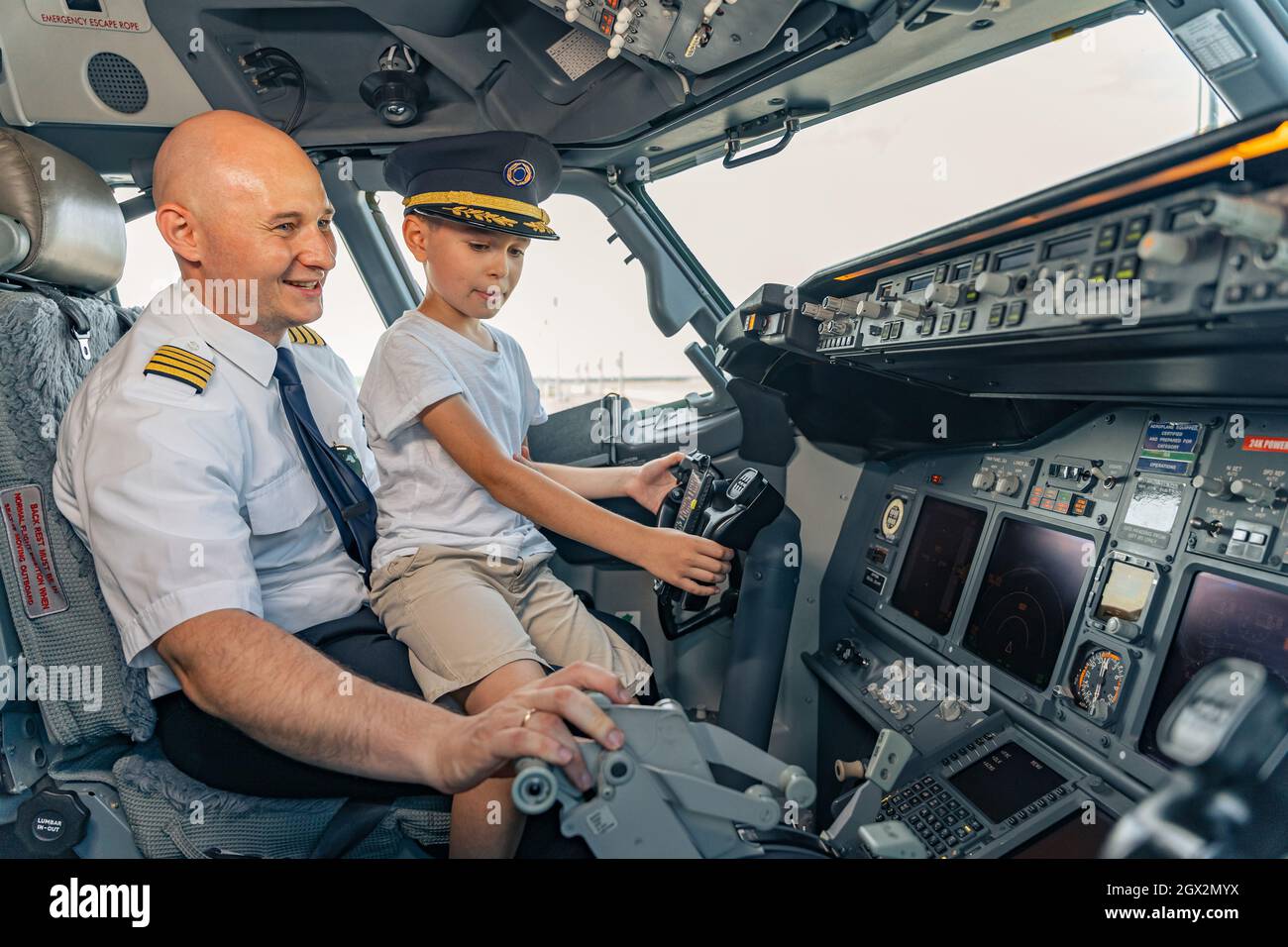 Smiling mature pilot and kid sitting in cabin Stock Photo - Alamy