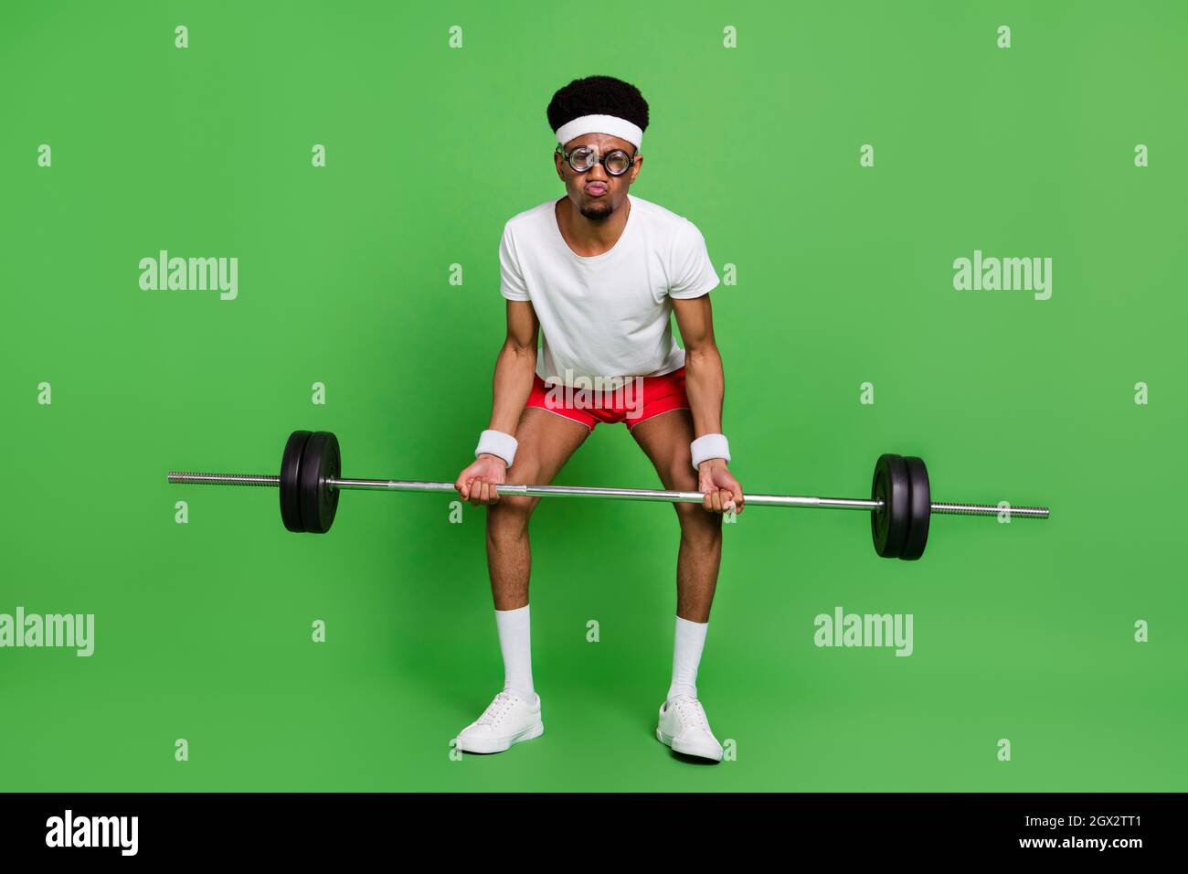 Photo of funny nerd bodybuilder guy lift heavy barbell grimace wear ...