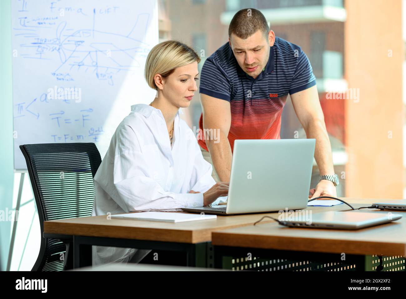 Horizontal shot of an employee showing something on a computer screen ...