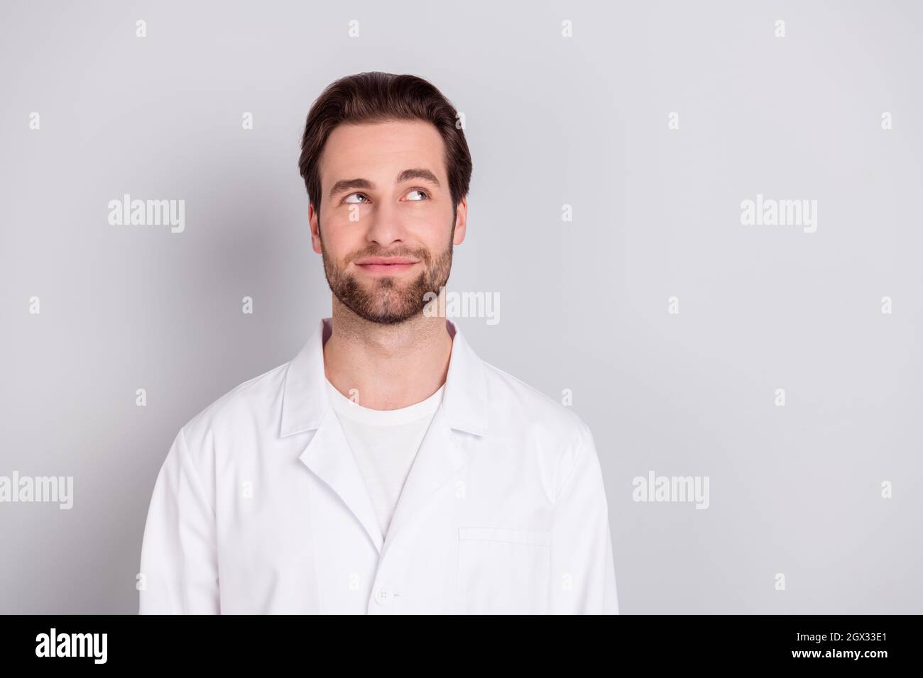 Photo of dreamy positive young doc man dressed white coat smiling ...