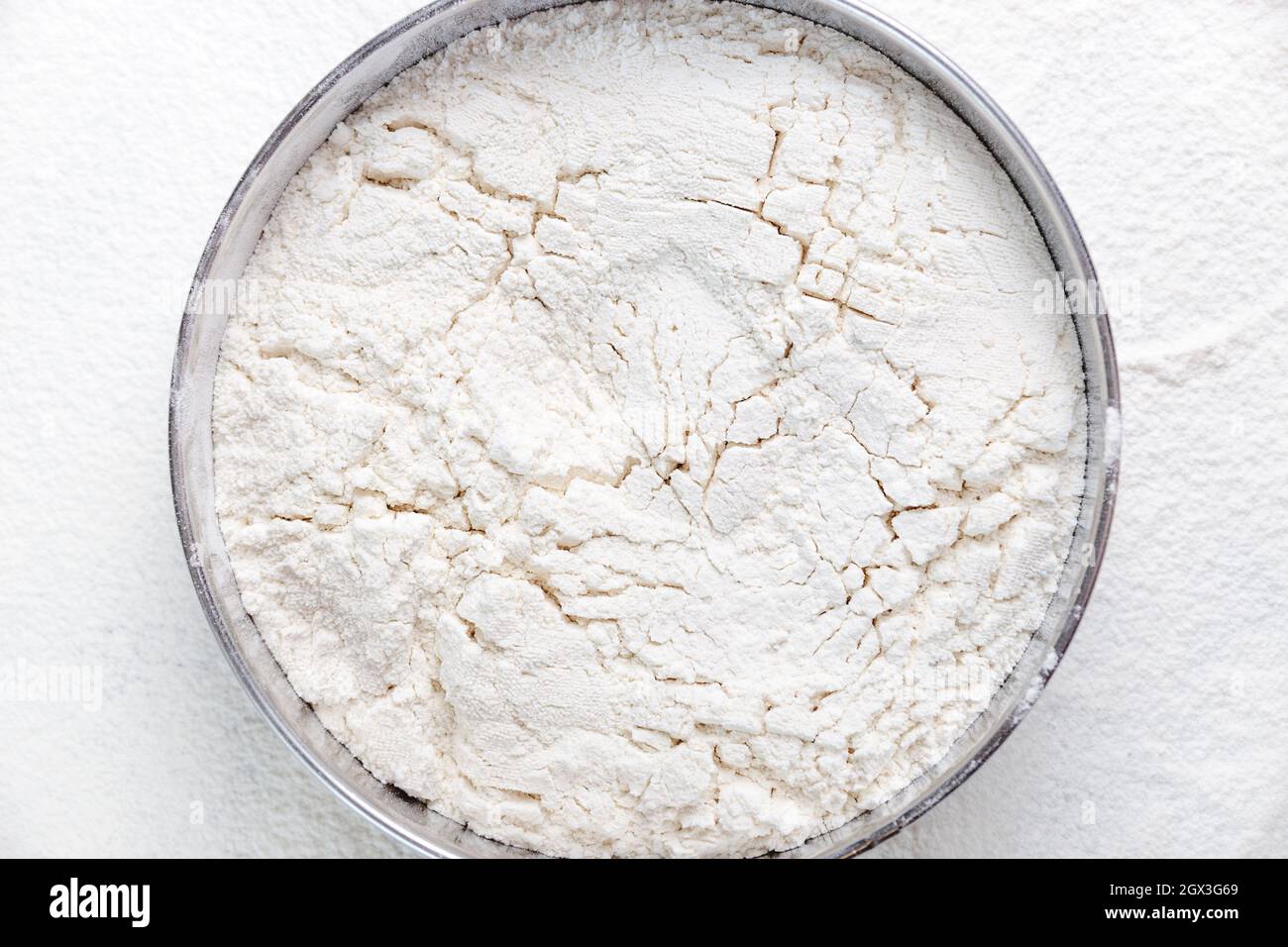 Flour in round metal bowl and scattered around on background. Flour ...