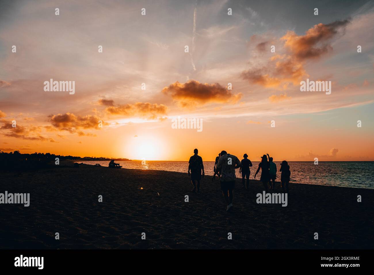 Silhouette of tourists enjoying the beach during a beautiful sunset ...