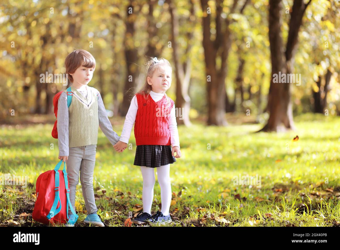 Children with briefcases for a walk in park. School break. The ...
