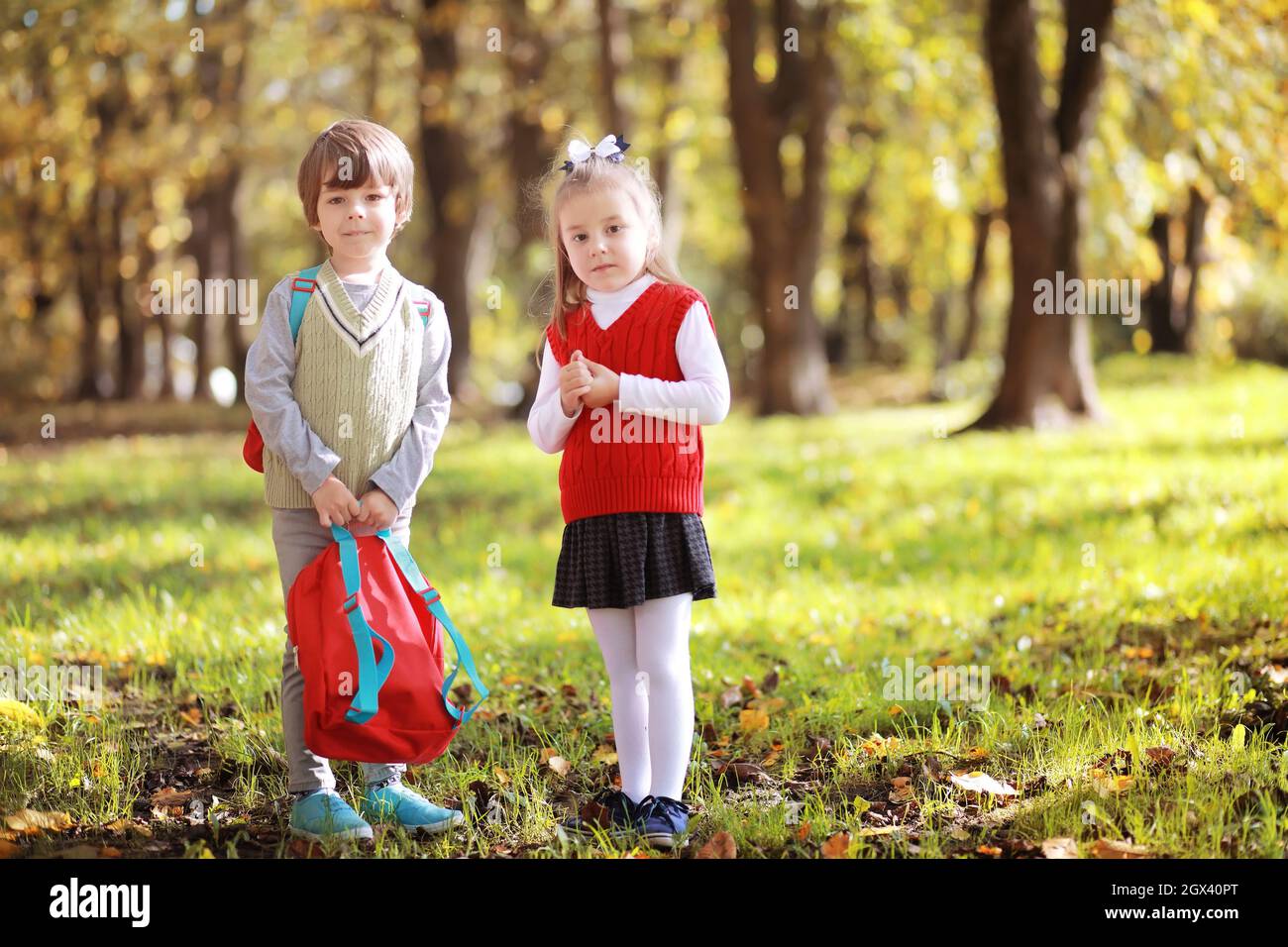 Children with briefcases for a walk in park. School break. The ...
