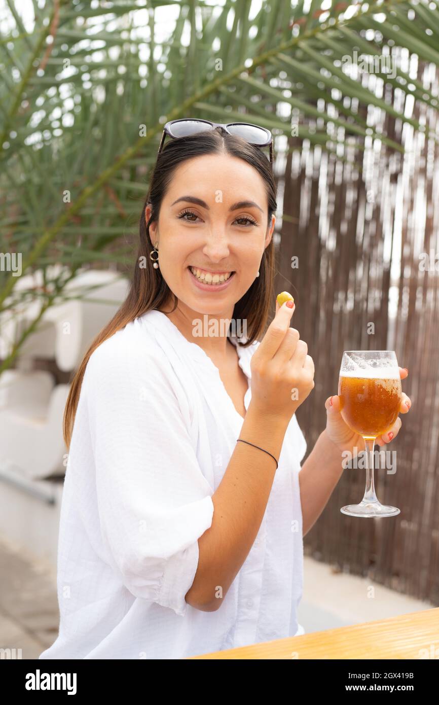 Smiling young woman drinking beer in a terrace Stock Photo - Alamy