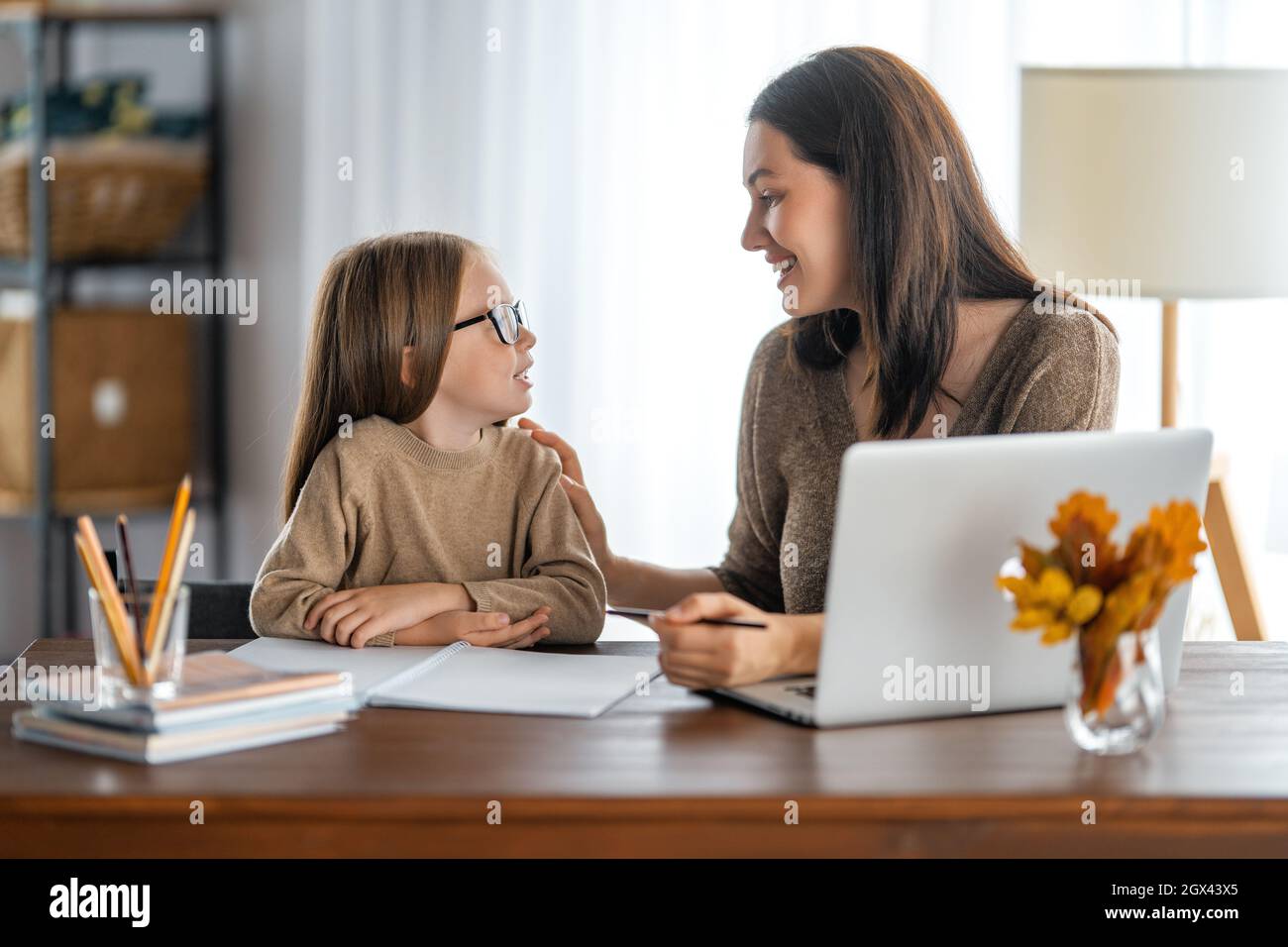 Back to school. Happy child and adult are sitting at desk. Girl doing ...