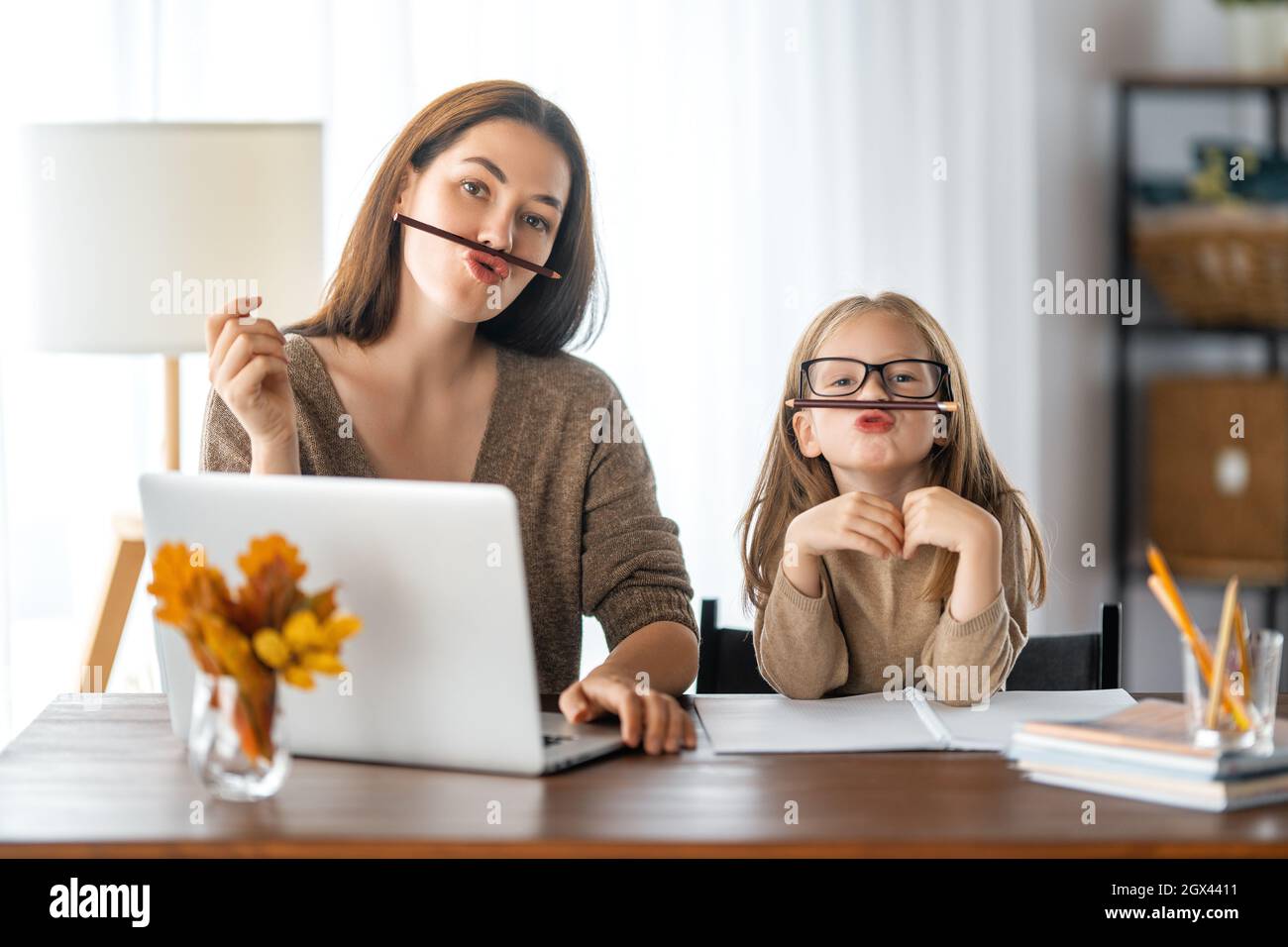 Back to school. Happy child and adult are sitting at desk. Girl doing ...