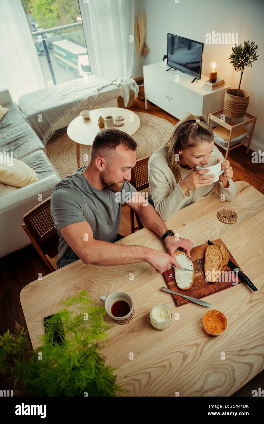 Caucasian couple sitting in kitchen making breakfast Stock Photo - Alamy
