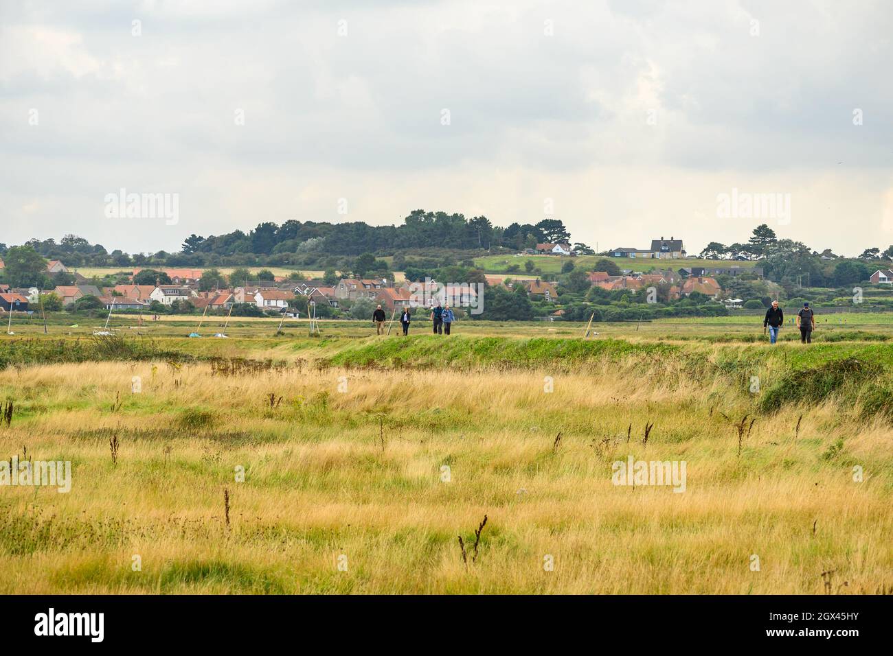 Walkers on the Blakeney Freshes circular footpath with Blakeney village ...