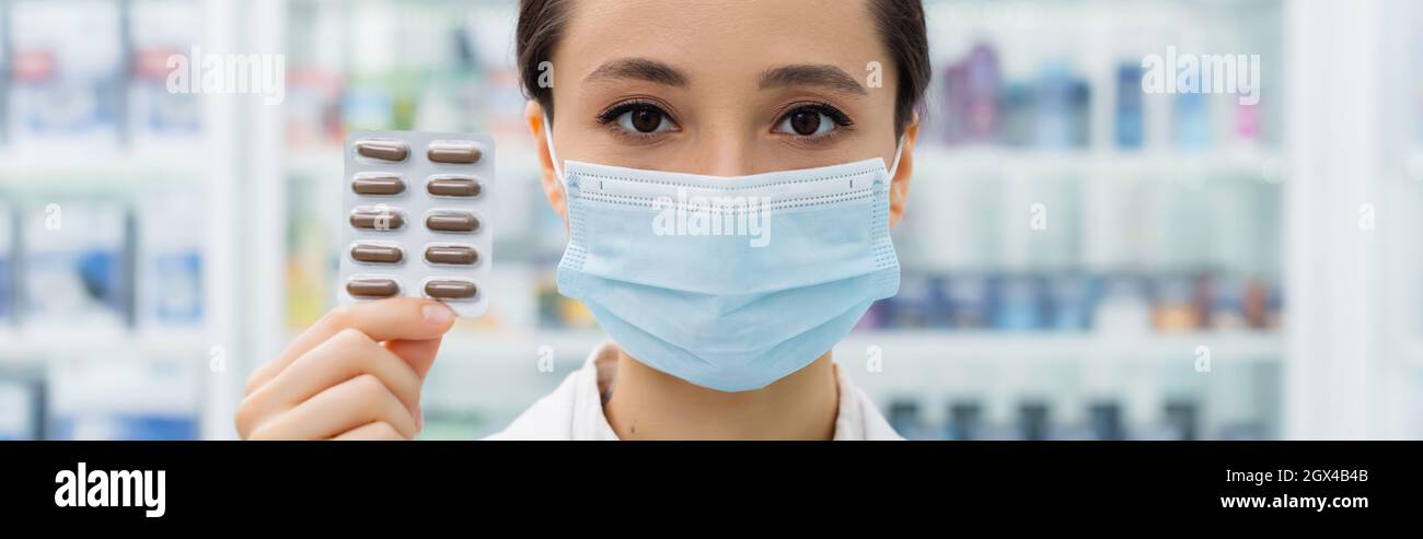 apothecary in medical mask holding blister pack with medication, banner ...