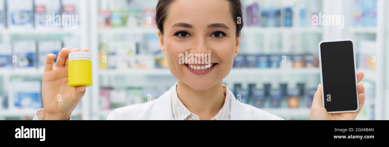 cheerful pharmacist in white coat holding smartphone with blank screen ...
