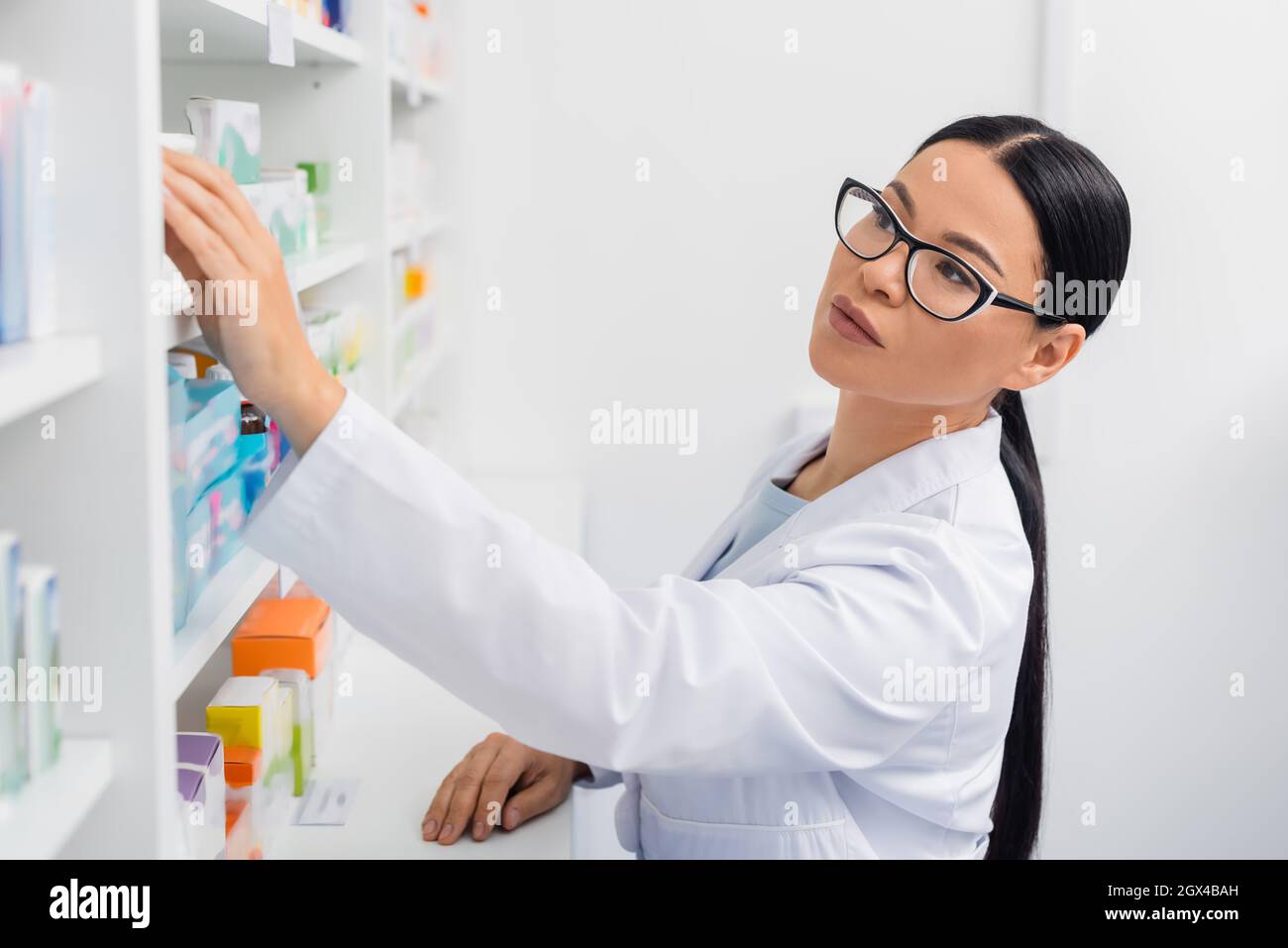 asian pharmacist in glasses reaching medication in drugstore Stock ...