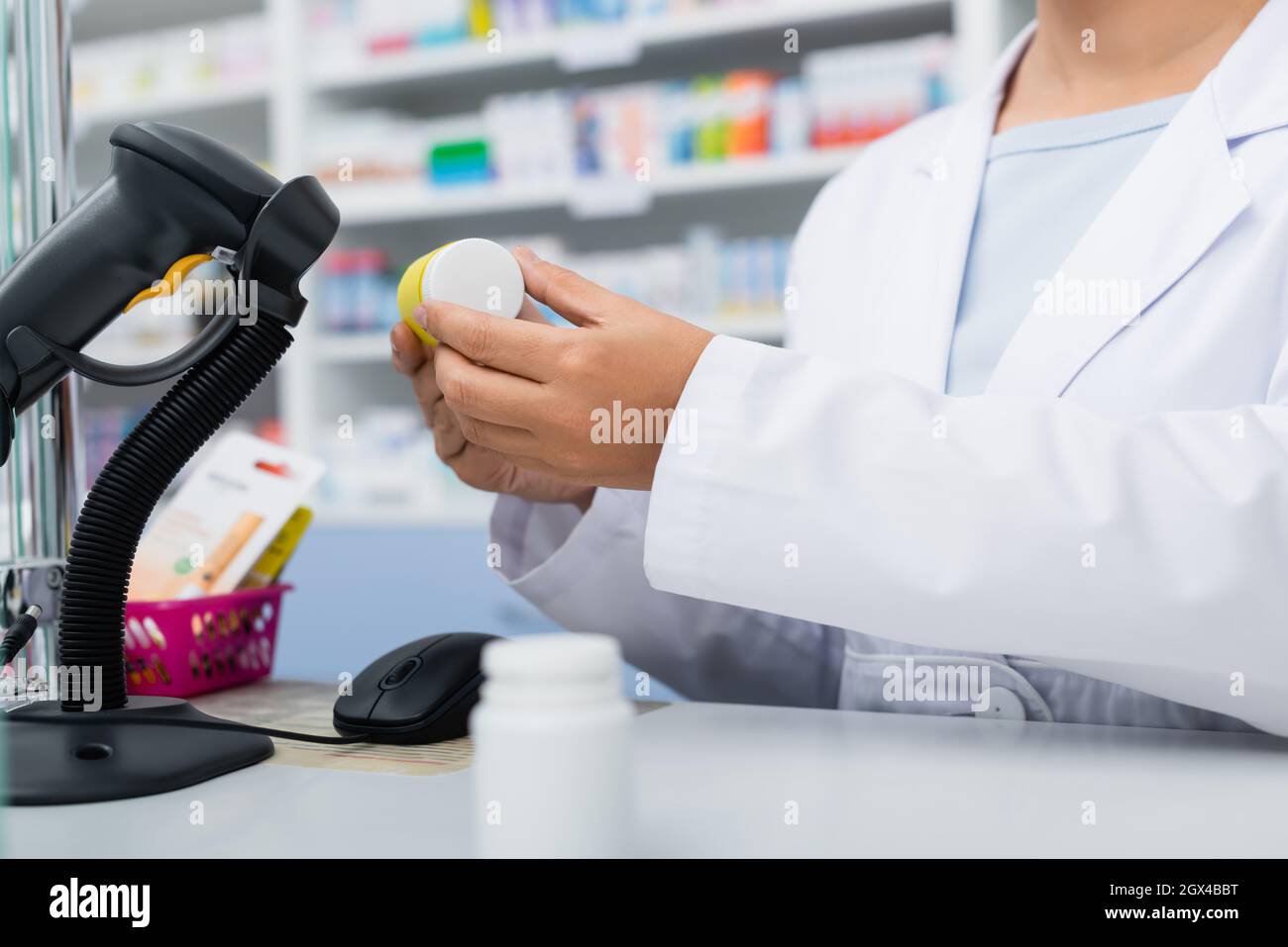 cropped view of pharmacist in white coat scanning bottle with ...