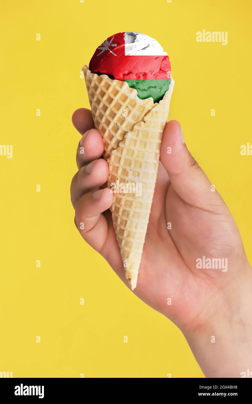 On a colorful background, a hand with ice cream in the form of the flag ...