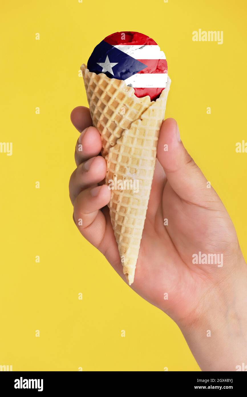 On a colorful background, a hand with ice cream in the form of the flag ...