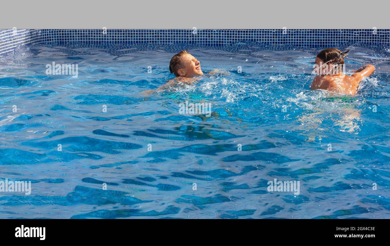 Boys swim and splash water in the pool. Summer vacation at the hotel ...