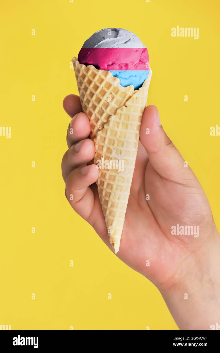 On a colorful background, a hand with ice cream in the form of the flag ...