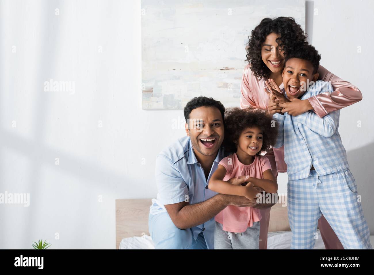 happy african american parents hugging kids while having fun in bedroom ...