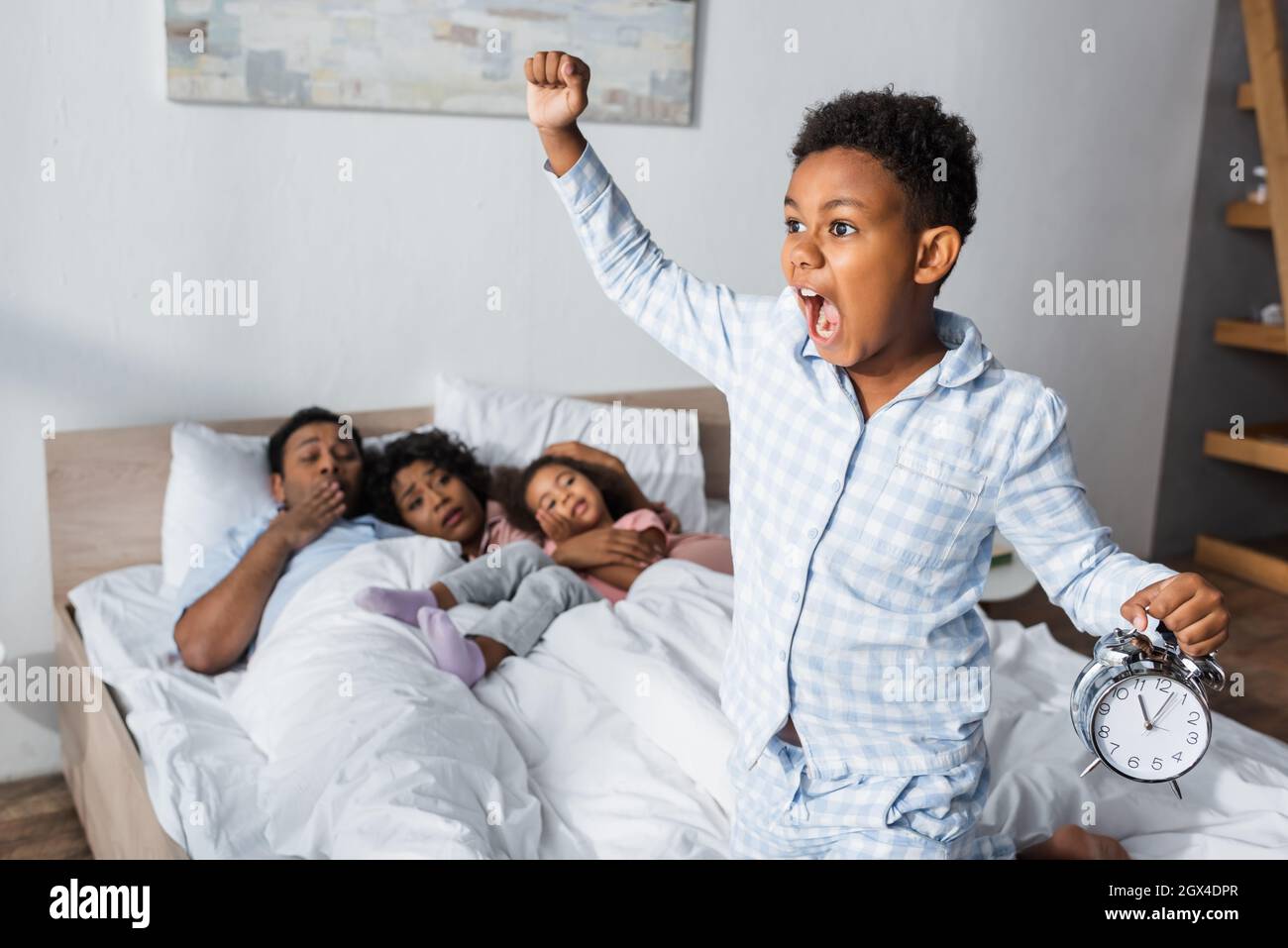 excited african american boy with alarm clock screaming and showing ...