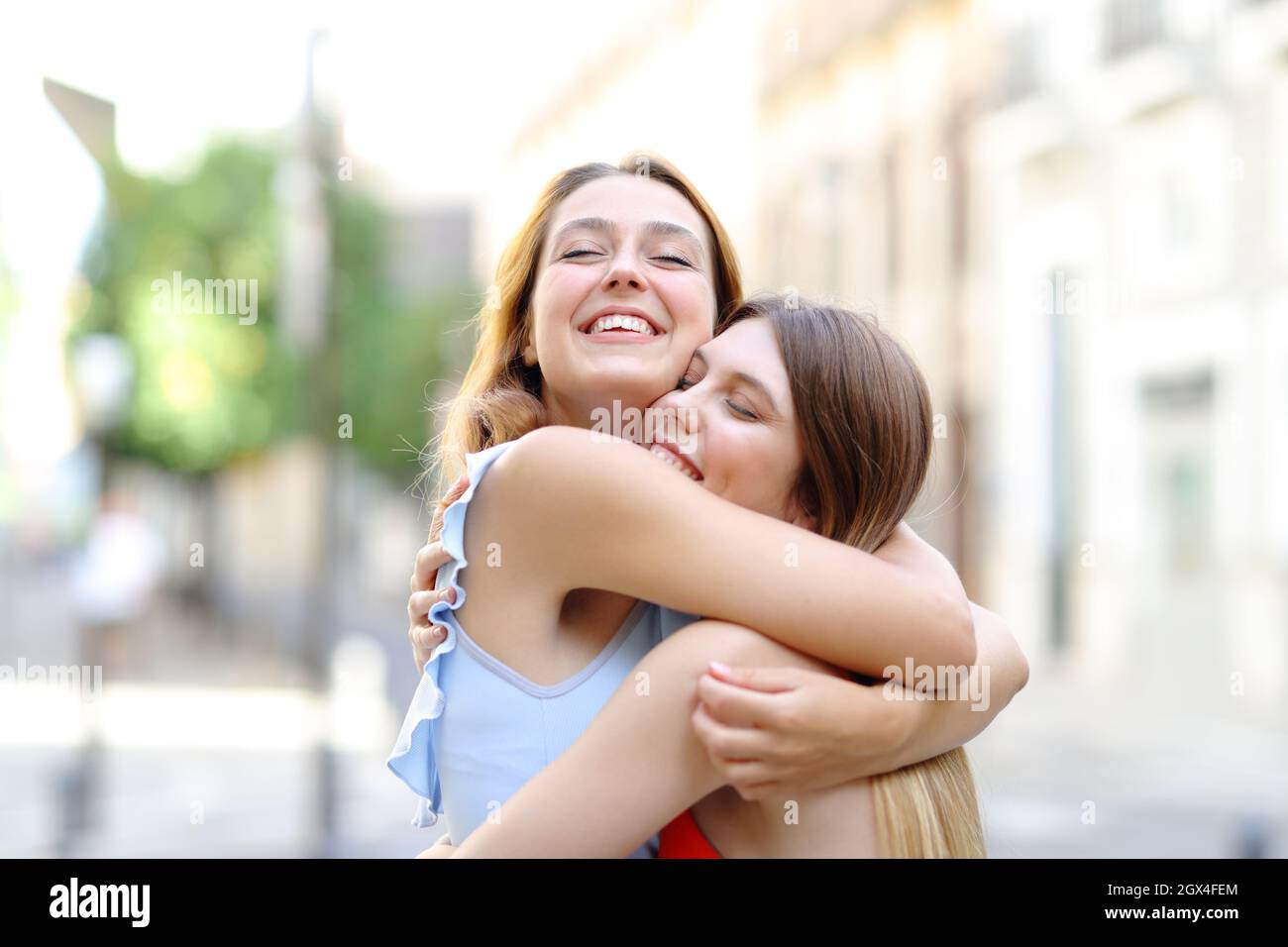 Two happy friends cuddling affectionate in the middle of the street ...