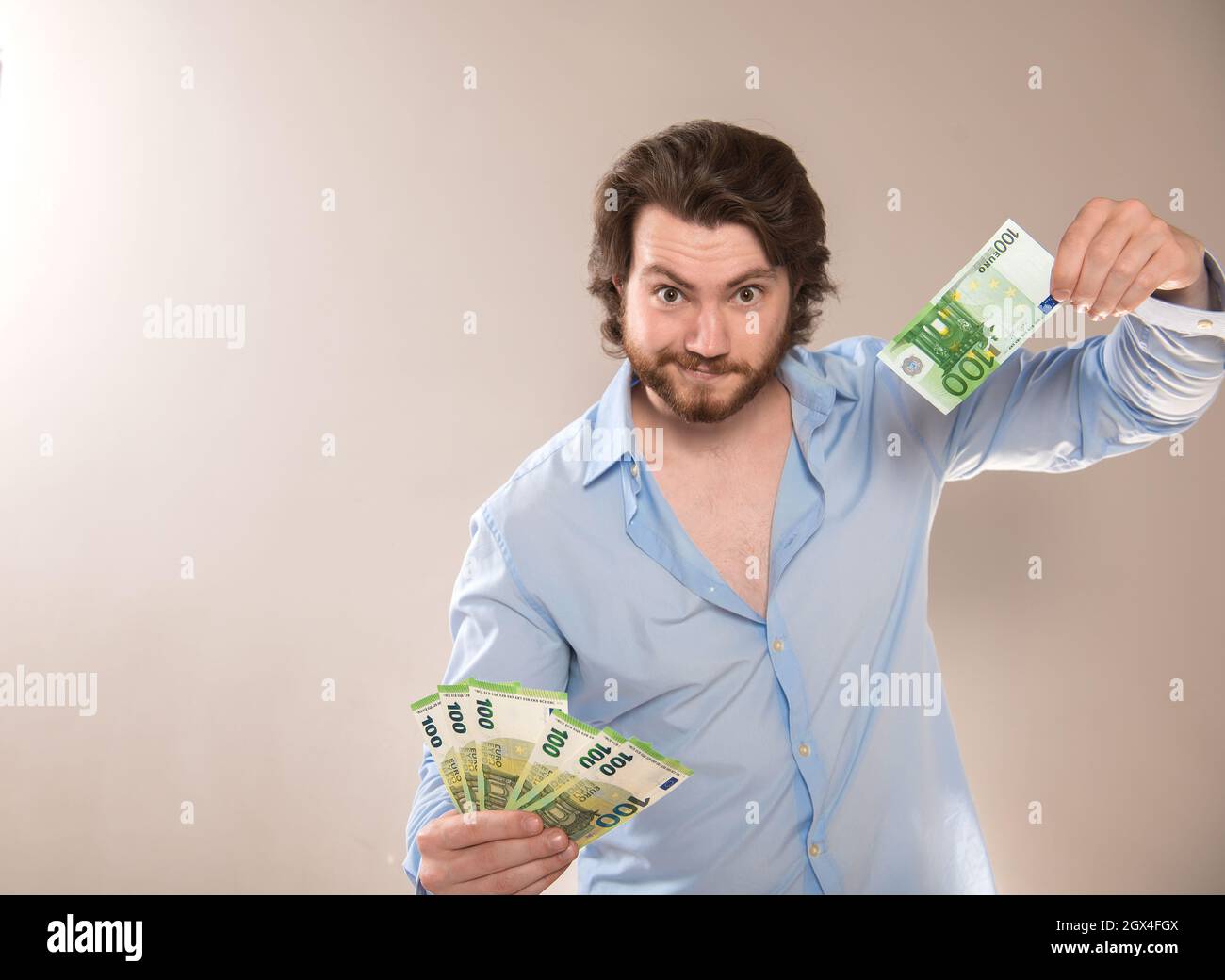 a frivolous rich young man holds 100 euro banknotes in his hands and ...