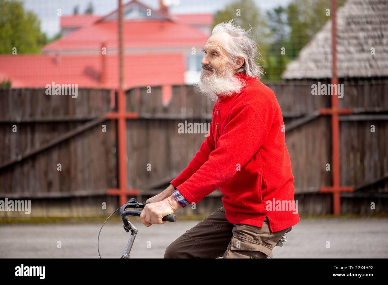 sad old bearded man riding a bicycle wearing a red sweater, hair ...
