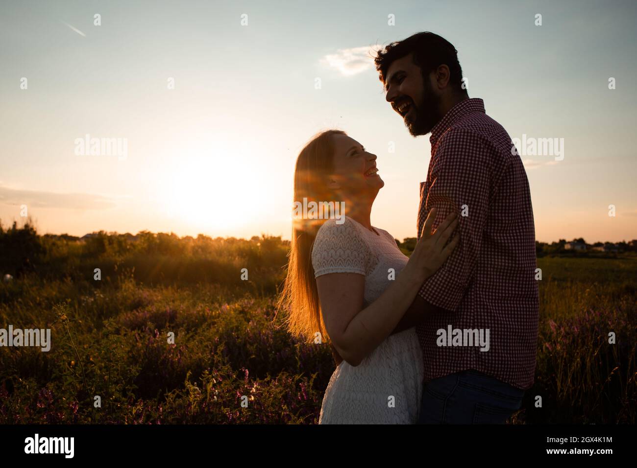 Embracing couple in rays of setting sun Stock Photo - Alamy