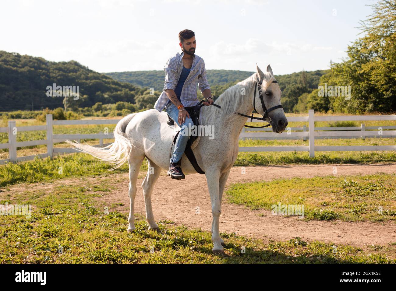 The handsome man rides a horse on a ranch Stock Photo - Alamy