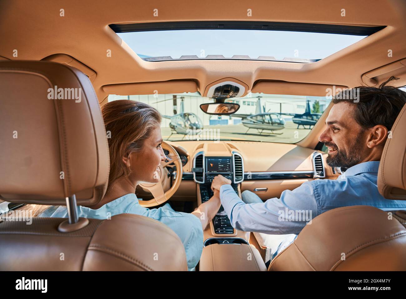 Romantic couple driving up helipad with helicopters Stock Photo - Alamy