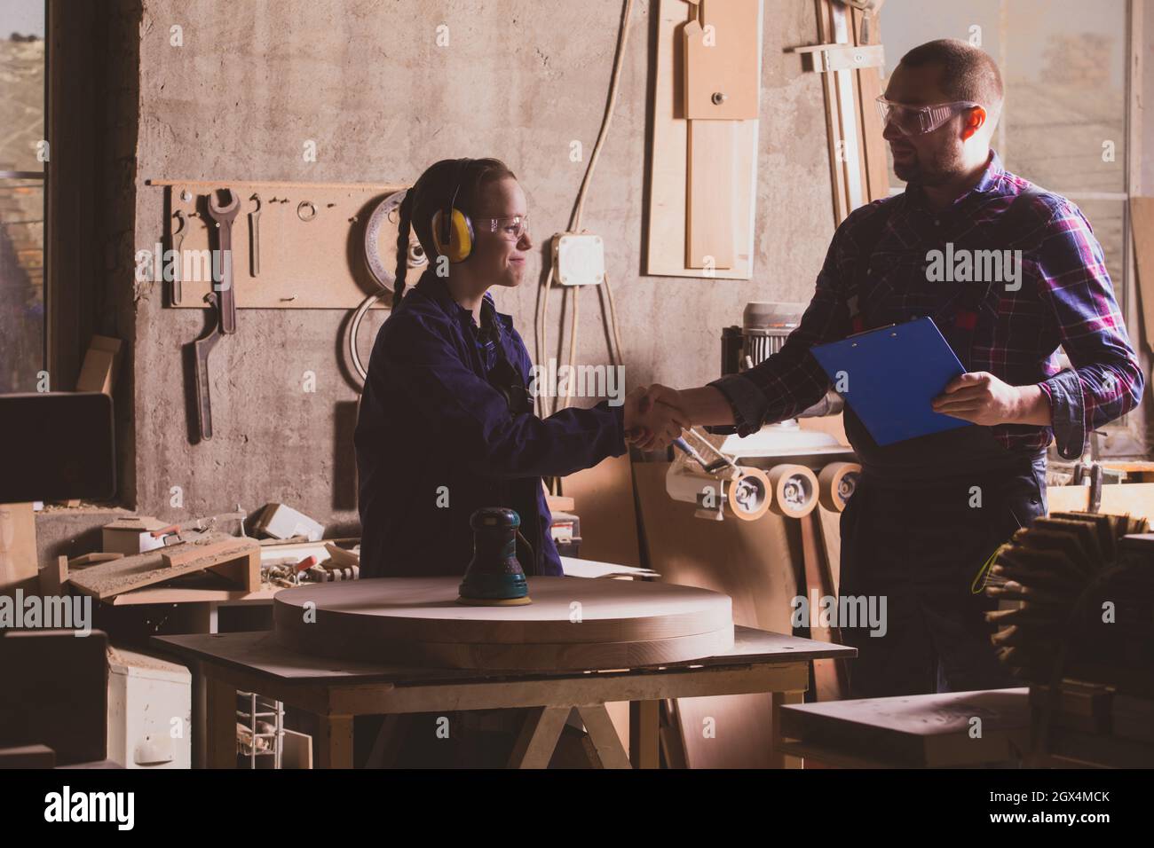 Adult carpenter congratulating teen boy after passing final practical ...