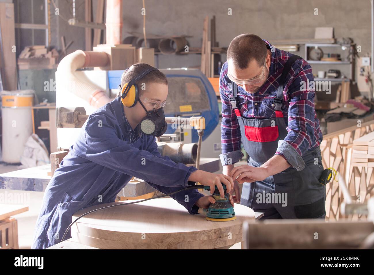 Experienced carpenter teaching young apprentice at workshop Stock Photo ...