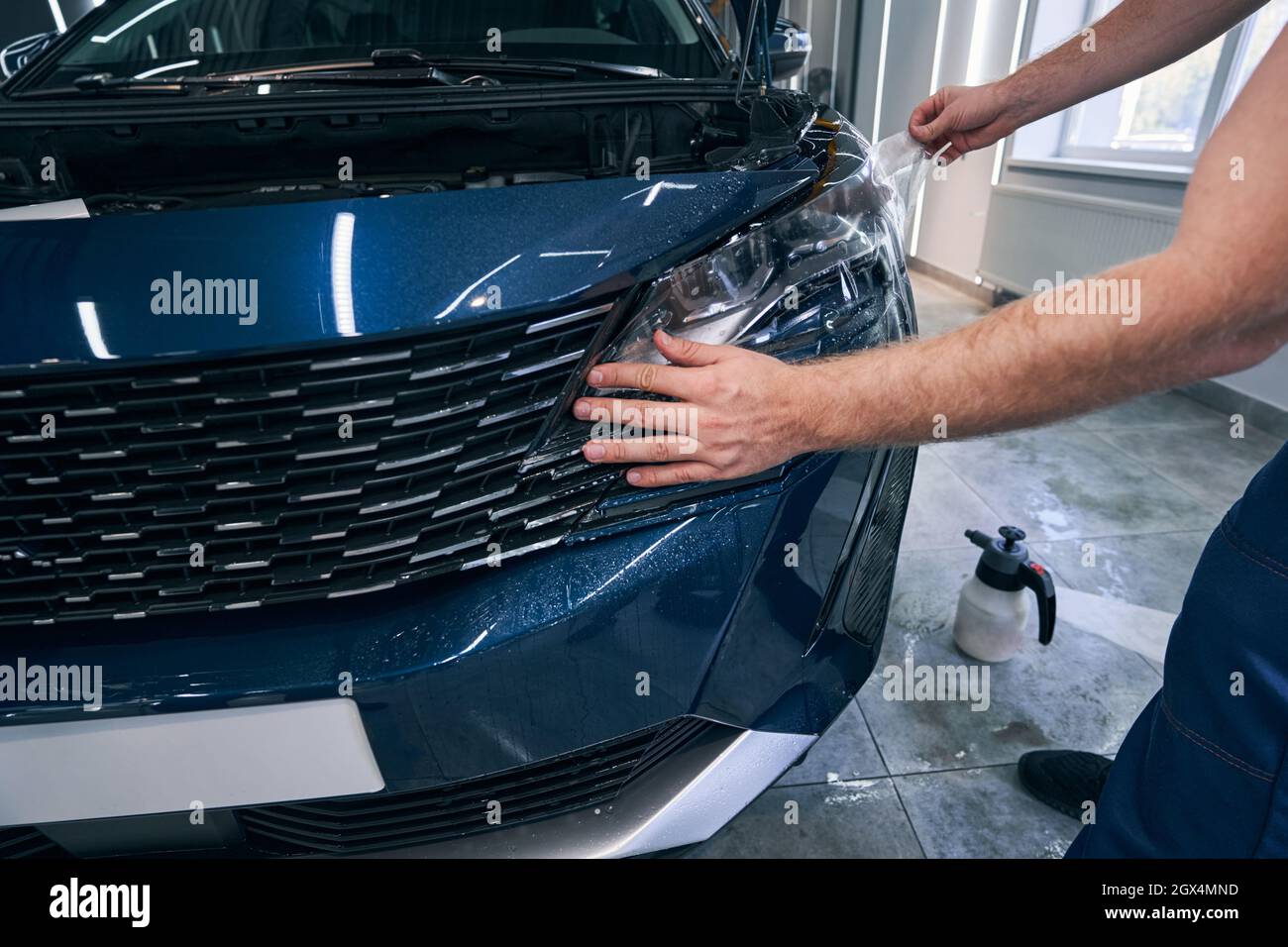 Closeup PPF installation on front headlight. Paint protection film ...