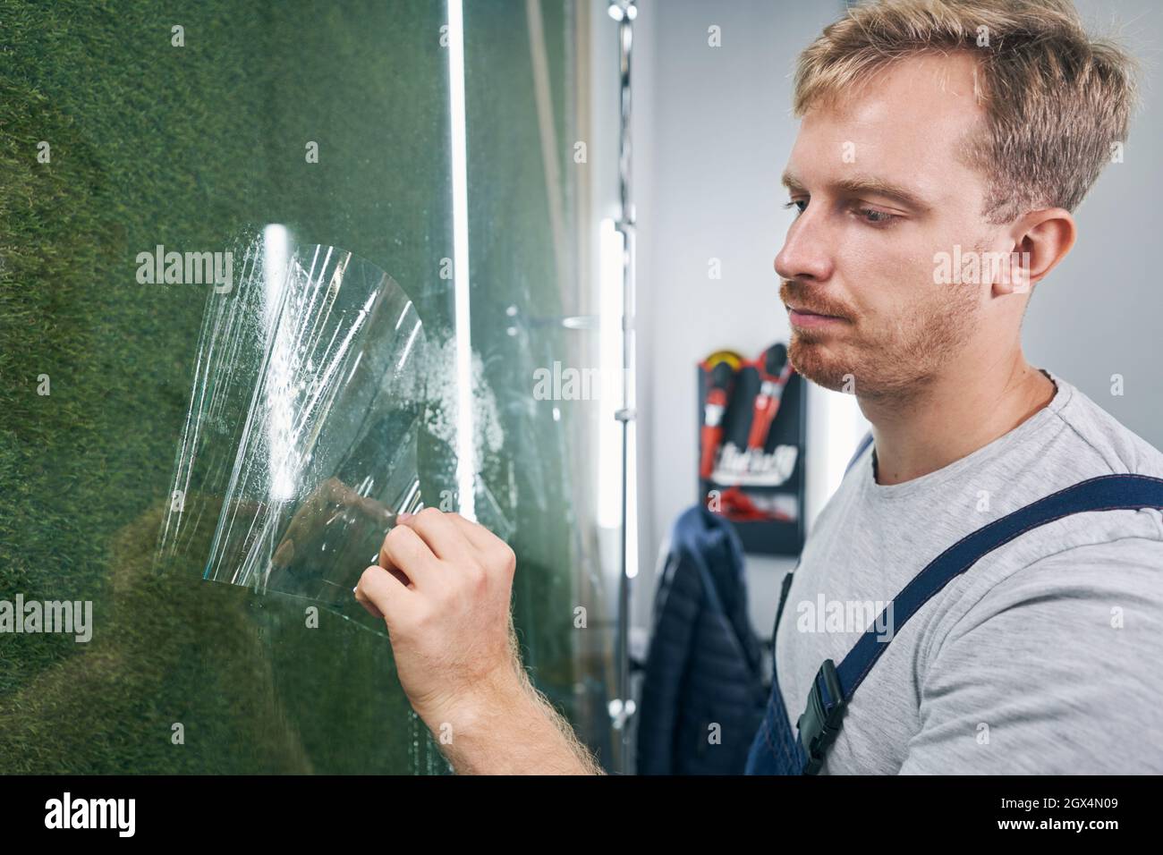 Car service worker man gets protective film closeup. PPF installation ...