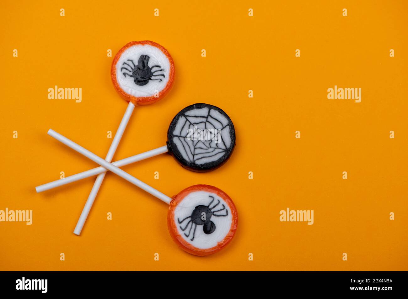 Halloween candy with black spiders and cobweb on orange color ...