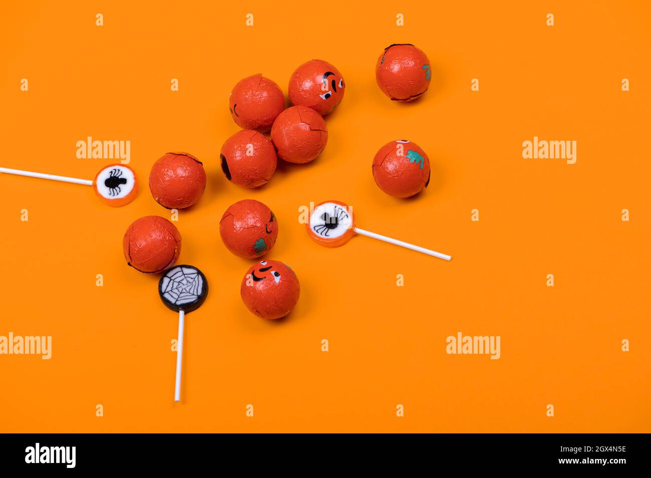 Halloween candy with black spiders,pumpkins and cobweb on orange color ...