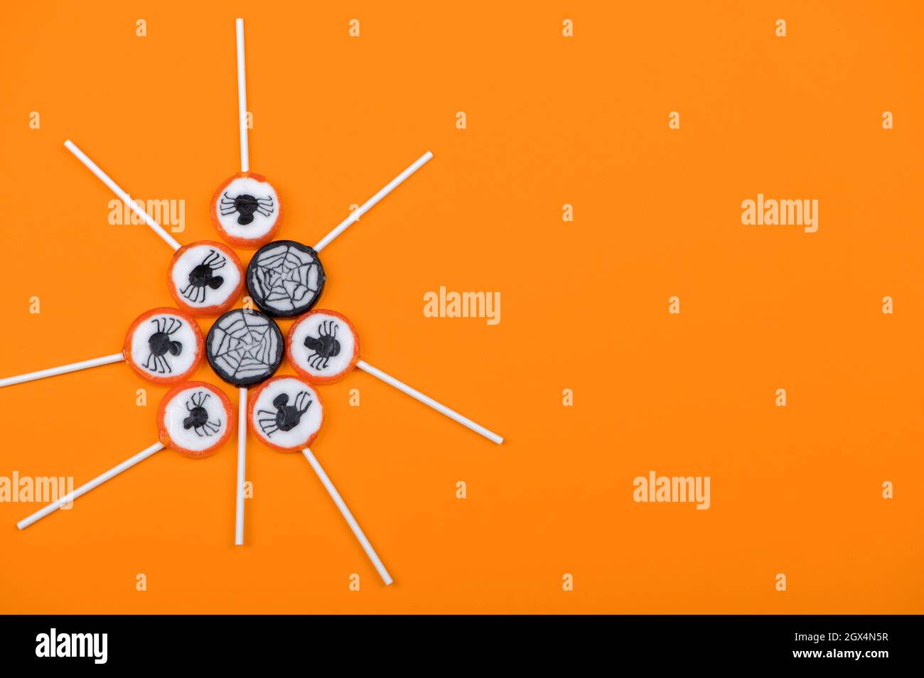 Halloween candy with black spiders and cobweb on orange color ...