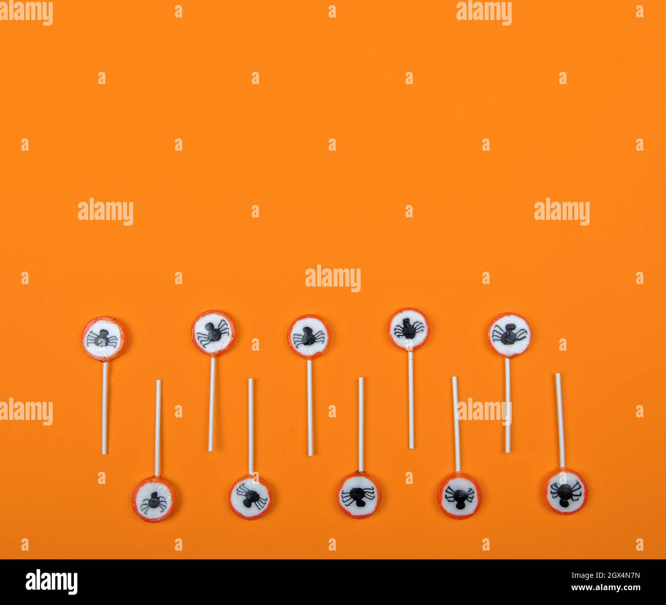 Halloween candy row with black spiders and cobweb on orange color ...
