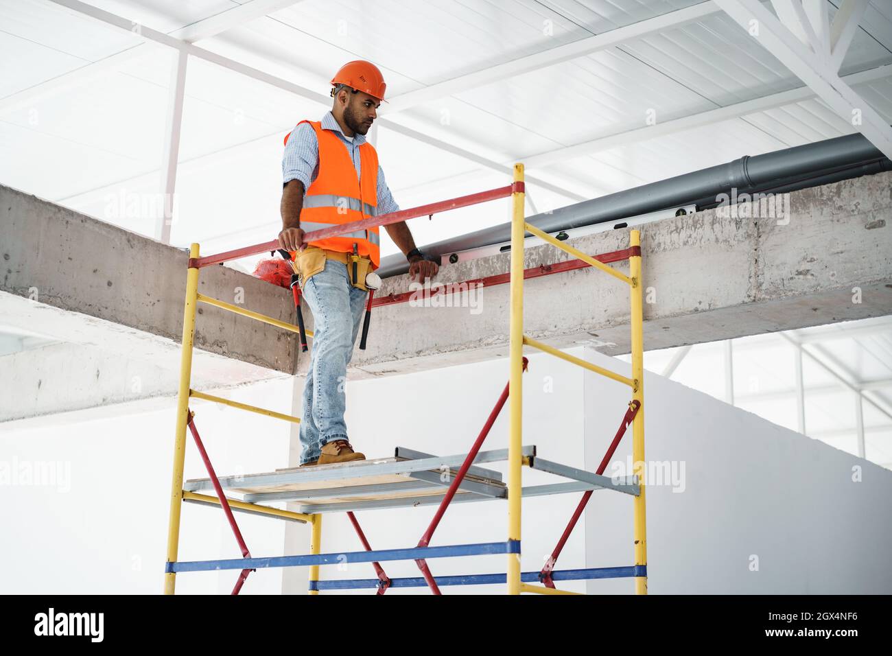 Young handsome builder climbing on scaffolding at construction site ...