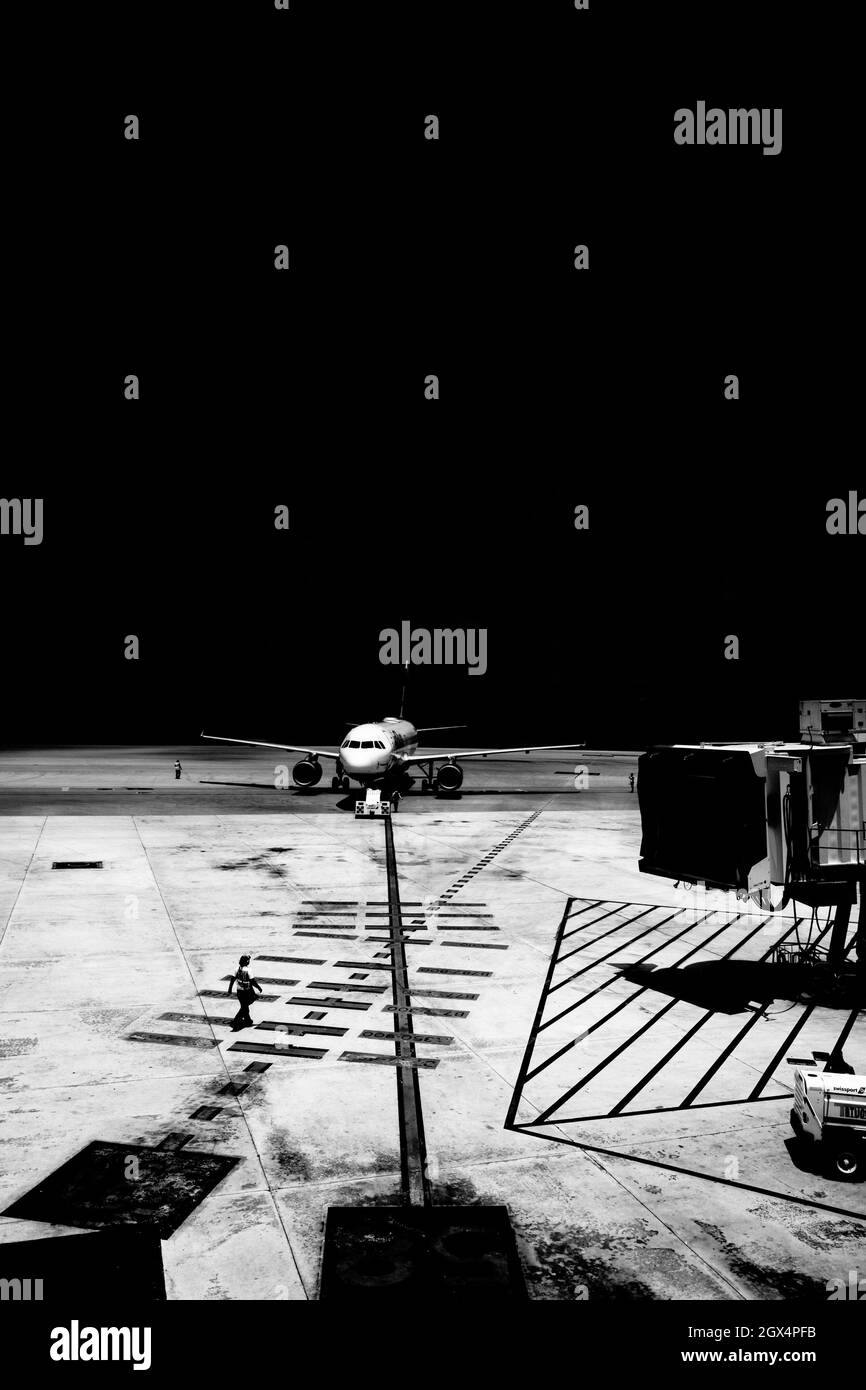 Grayscale of a plane on the platform of an airport at night Stock Photo ...