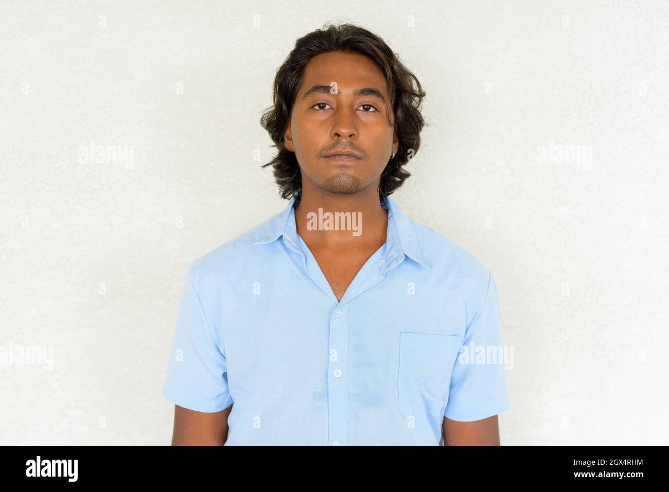 Portrait of handsome young Indian man against plain background outdoors ...