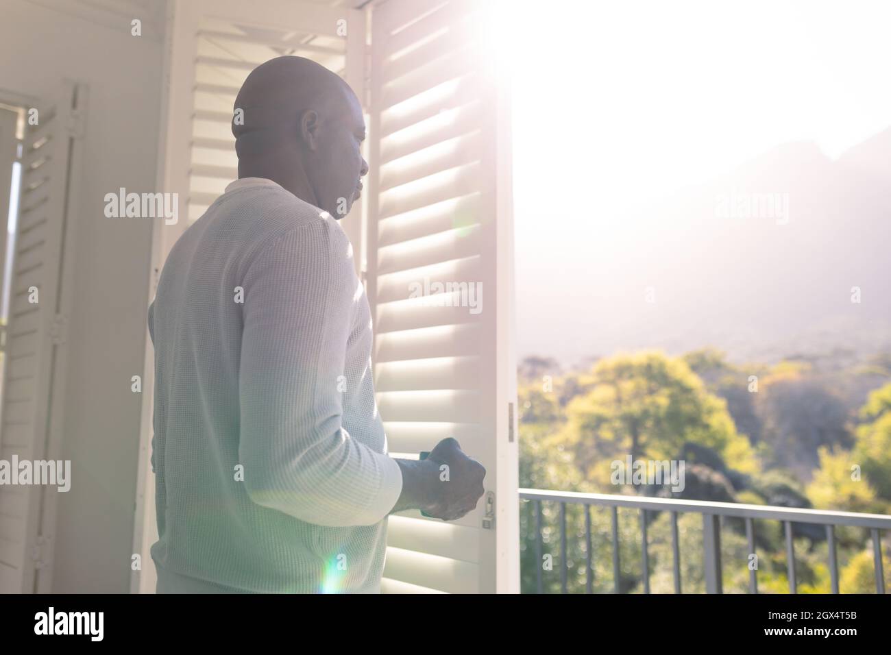 African american senior man standing at window with coffee and looking ...