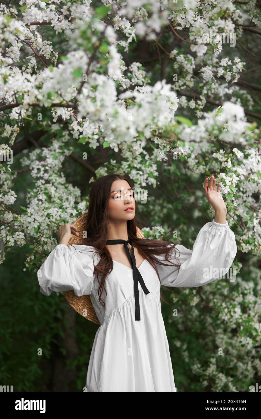 Portrait of a woman in the branches of a blooming apple tree. Beautiful ...