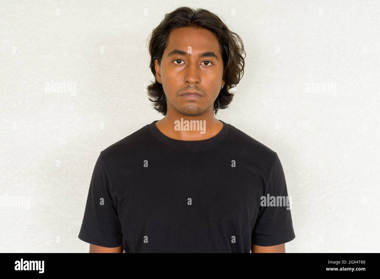 Portrait of handsome young Indian man against plain background outdoors ...