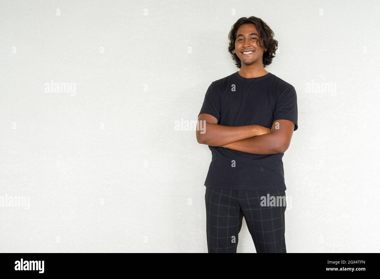 Portrait of handsome young Indian man against plain background outdoors ...