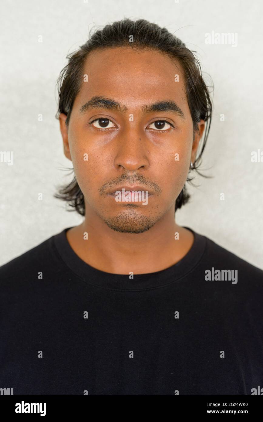 Portrait of handsome young Indian man against plain background outdoors ...