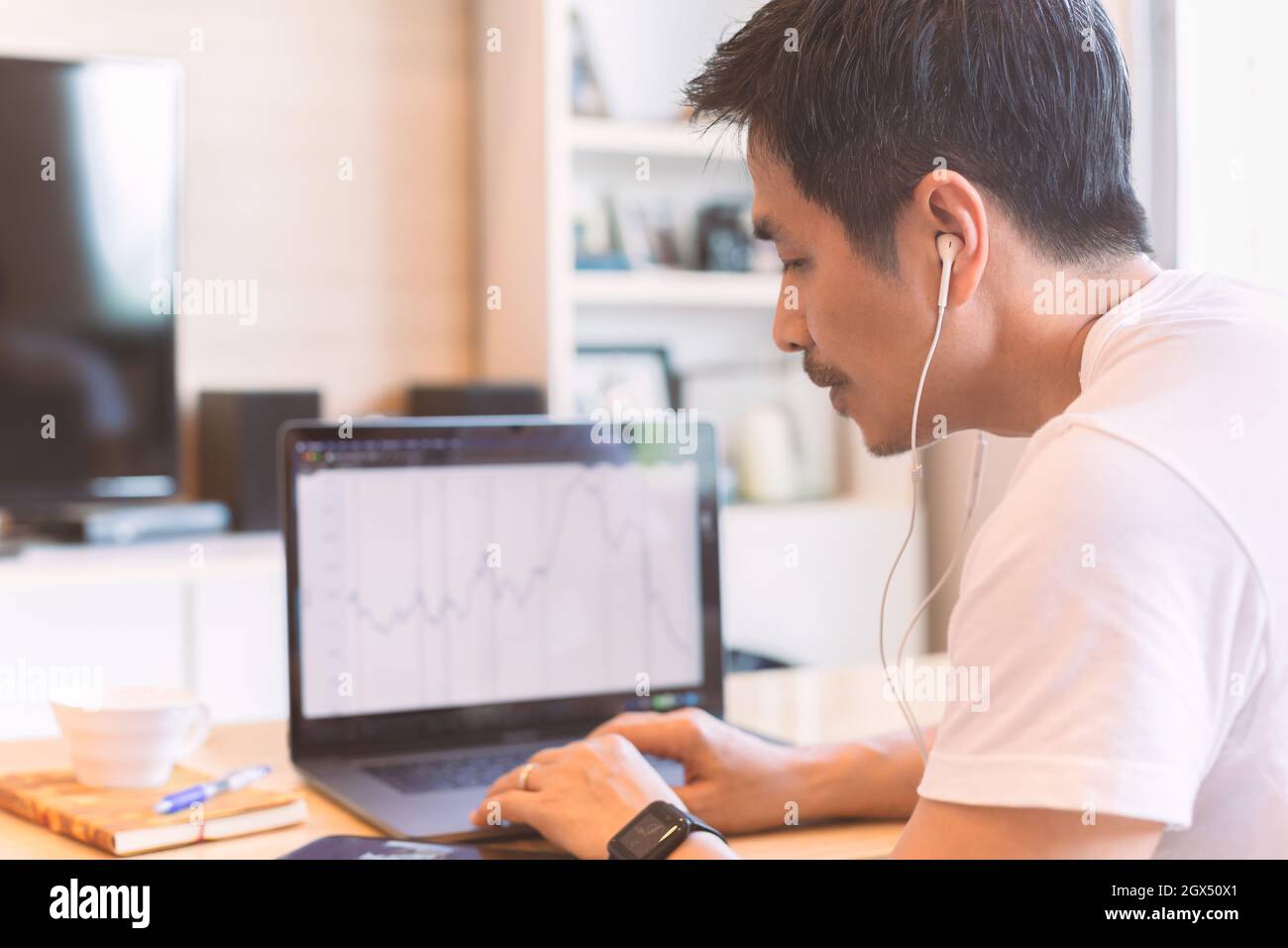 Man listening to music while working on laptop iat home Stock Photo - Alamy