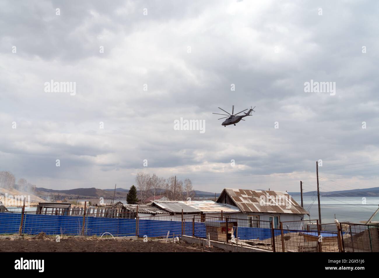 A helicopter flies over a forest fire over a rural village house in ...