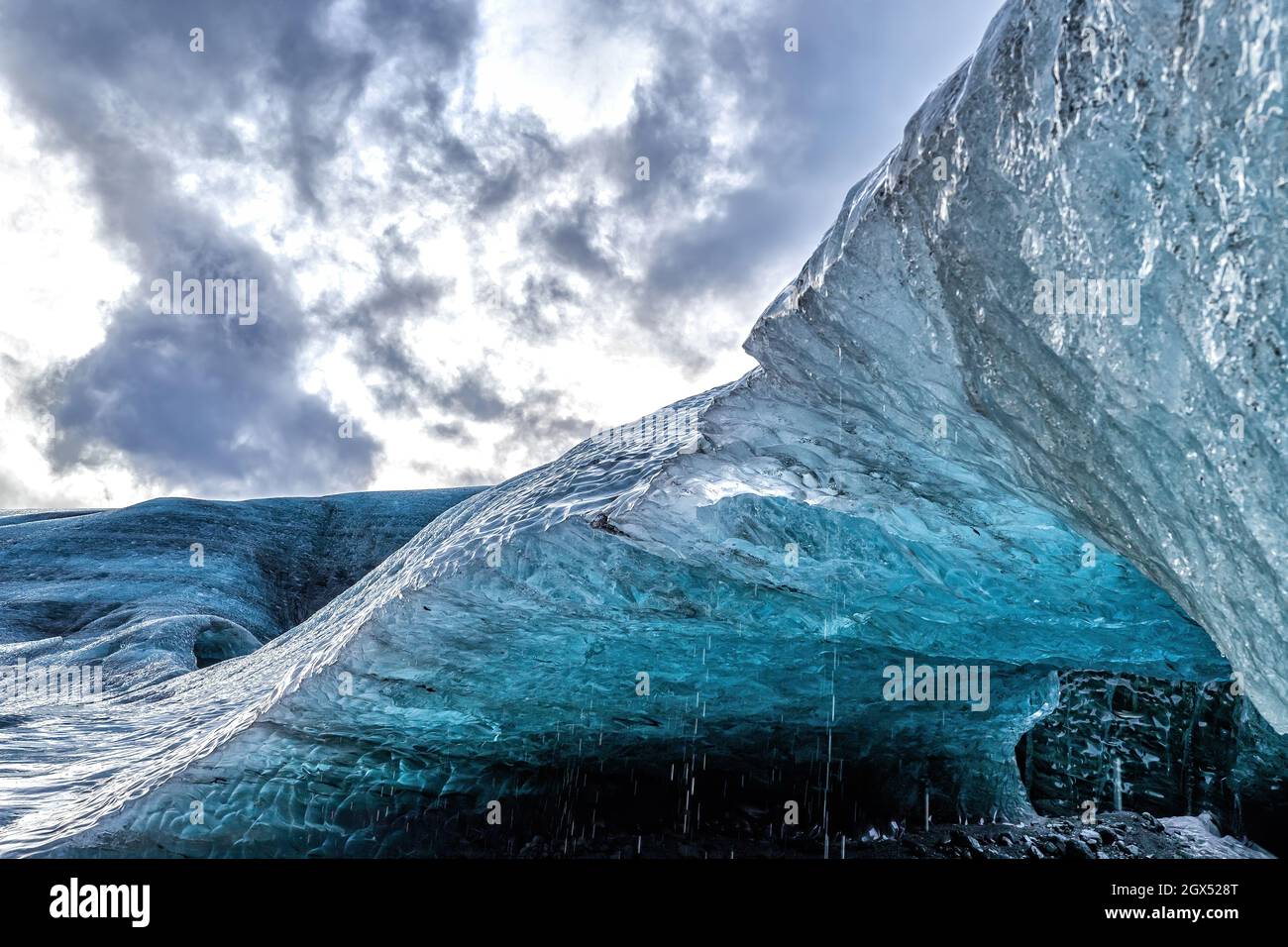 The overhang of a glacial ice cave in Iceland. The caves are coloured ...