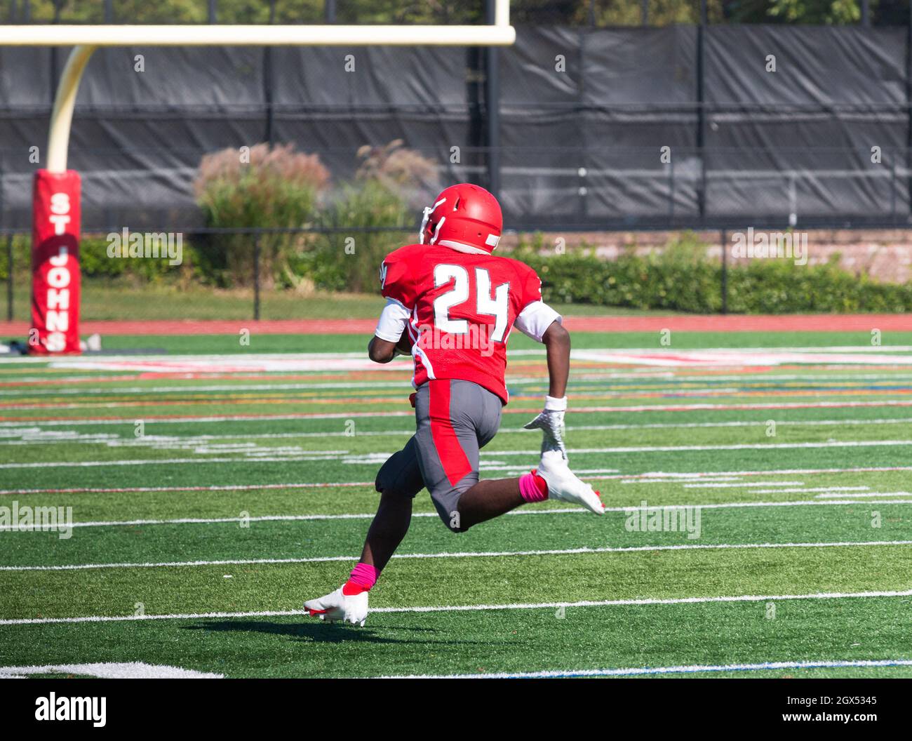 Rear view of a high school football player running into the end zone ...
